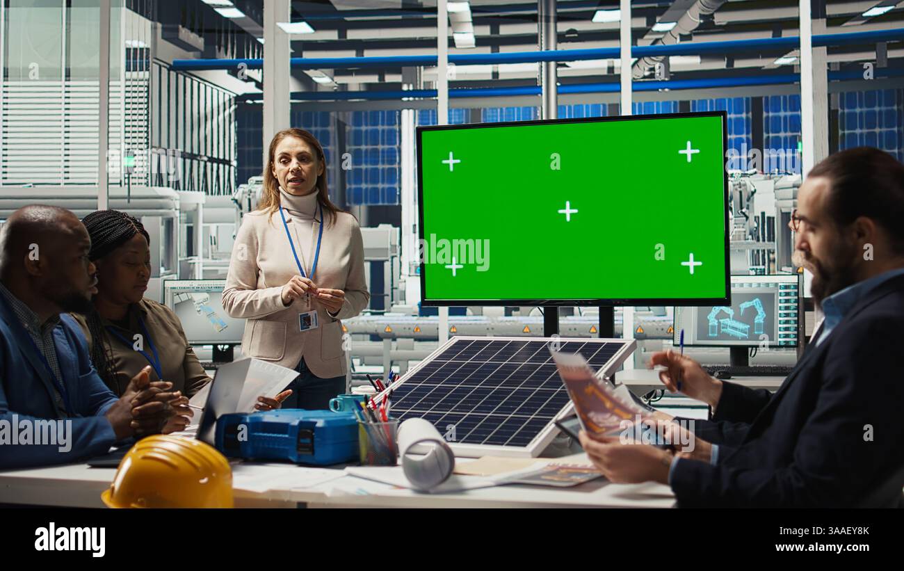 Factory engineers look over assembly lines schematics during business meeting in front of green ...