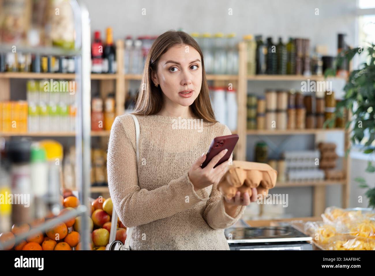 Female shopper scanning barcode on egg carton with phone in store Stock ...