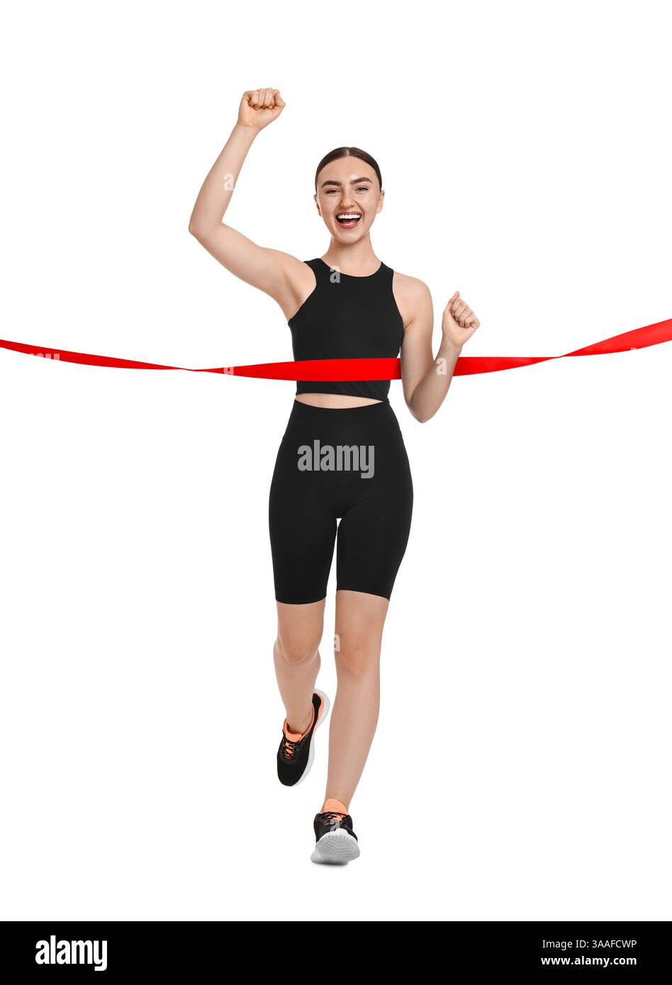 Happy sportswoman crossing red finish line ribbon on white background ...