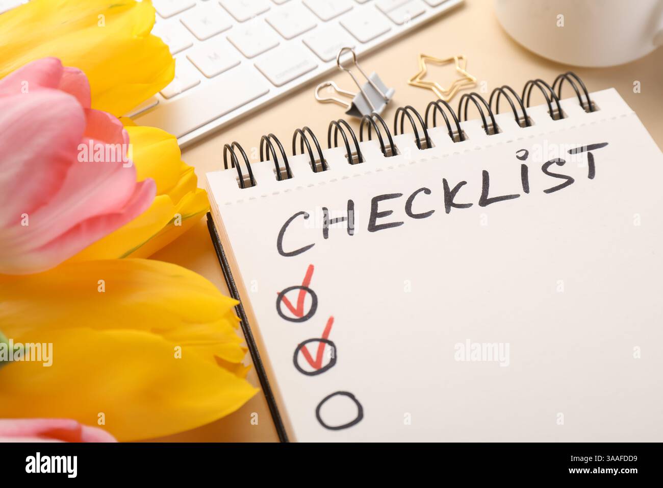 Checklist, keyboard, paper clips and tulips on beige background ...