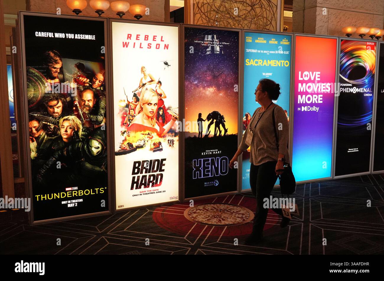 A CinemaCon attendee walks past advertisements for upcoming films on ...