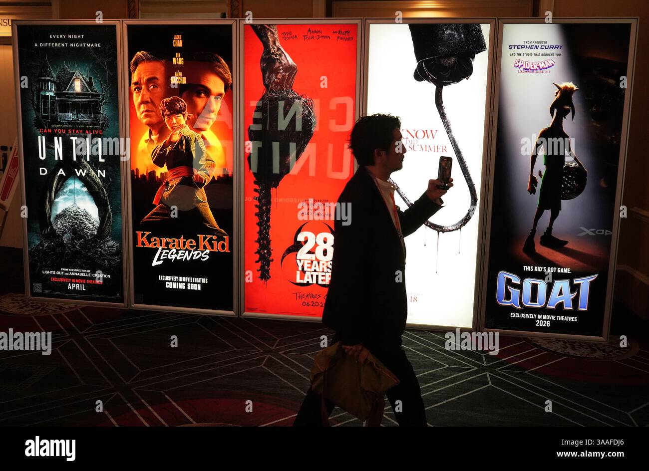 A CinemaCon attendee walks past advertisements for upcoming films on ...