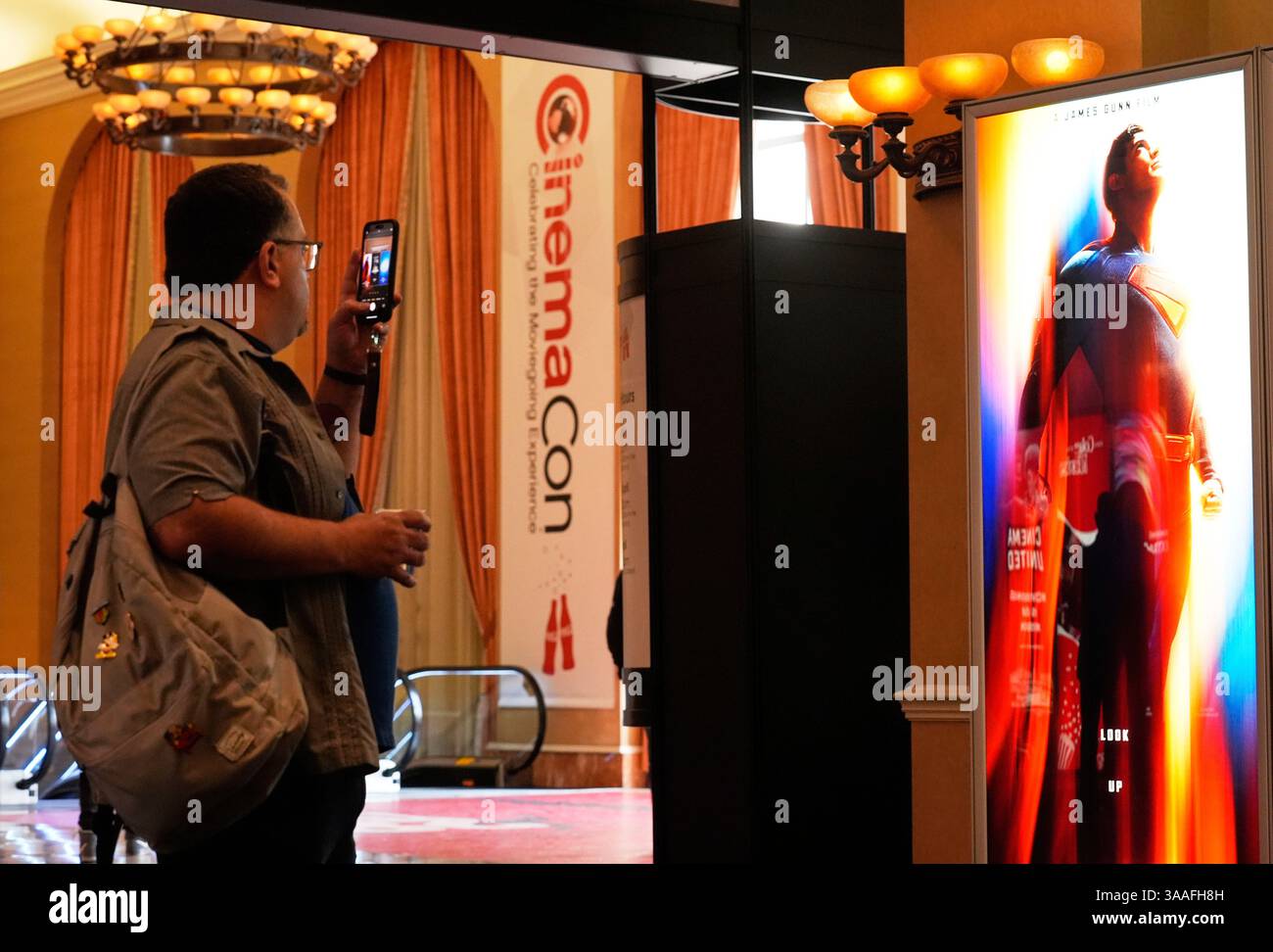 A CinemaCon attendee takes a picture of an advertisement for the ...