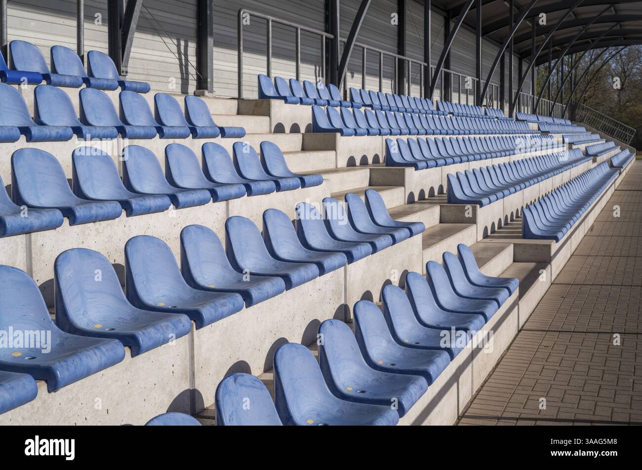 Rows of unoccupied blue plastic seats create a pattern in a ...