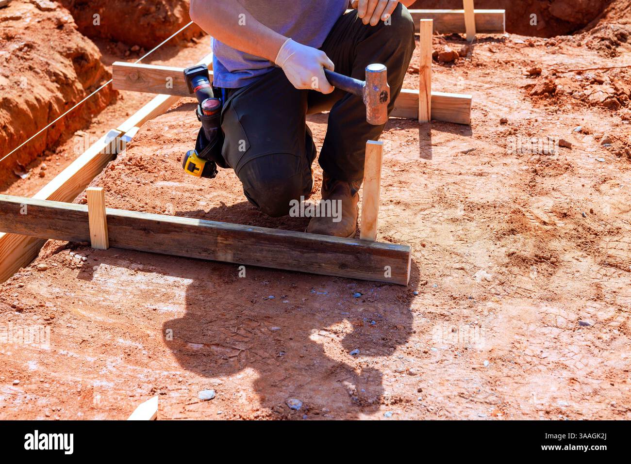 Construction worker is driving stakes into ground to establish ...