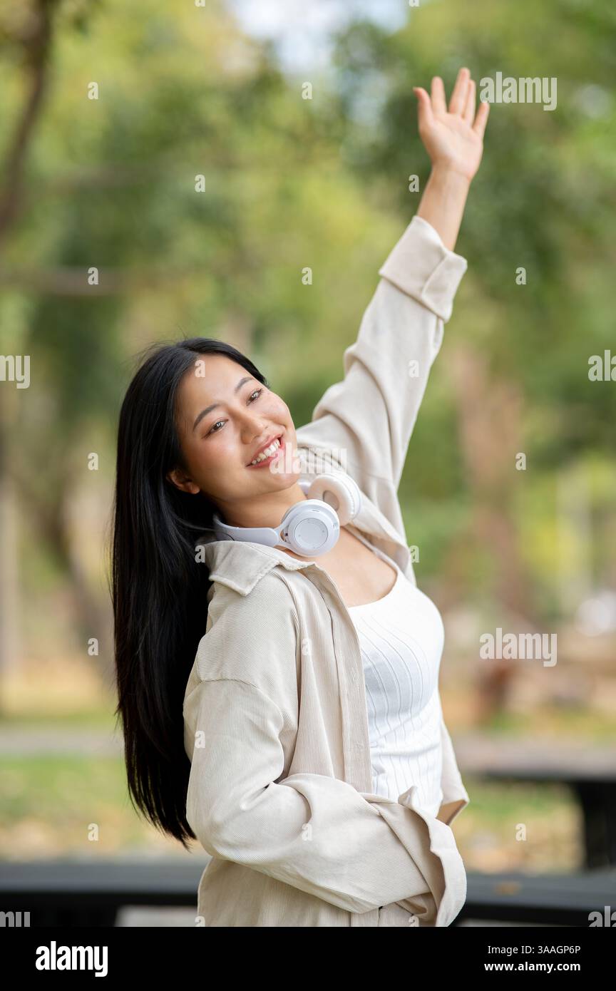 An asian woman is standing with one arm raised and looking ahead in the ...