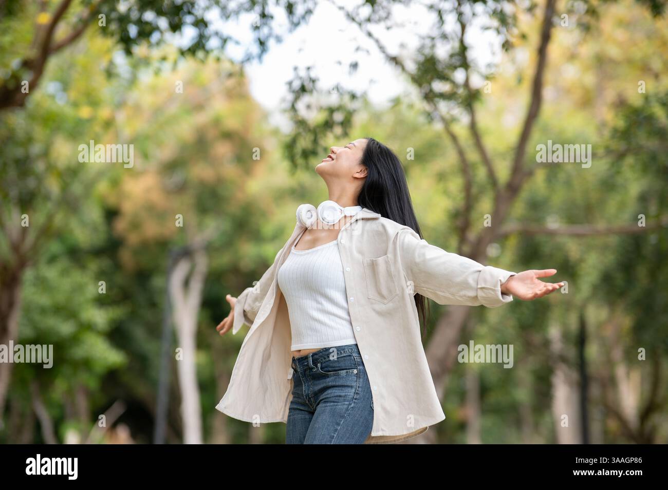 An asian woman is standing with open arms while turning around in the ...