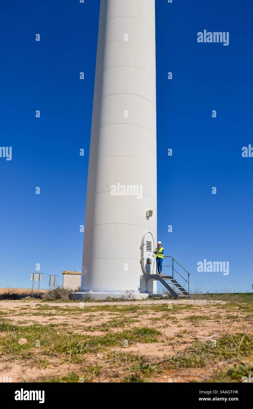 Female engineer using a digital tablet while standing at the base of a ...
