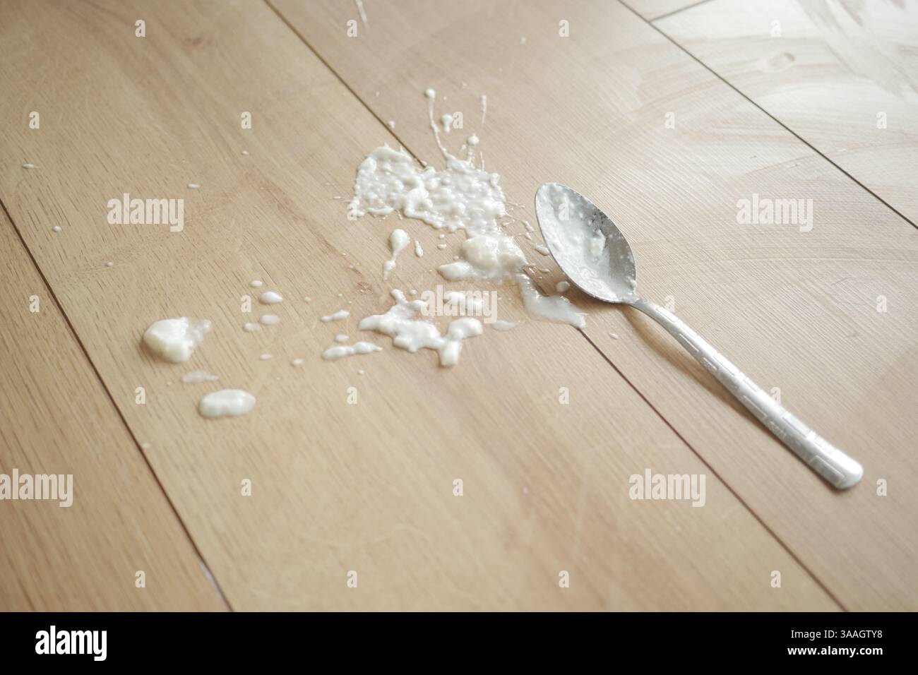 Spilled yogurt on wooden floor with spoon Stock Photo - Alamy