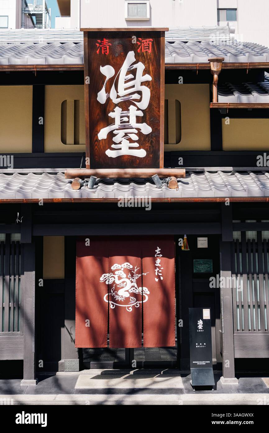 Wooden signboard and a crimson noren hanging in front of a store in a ...