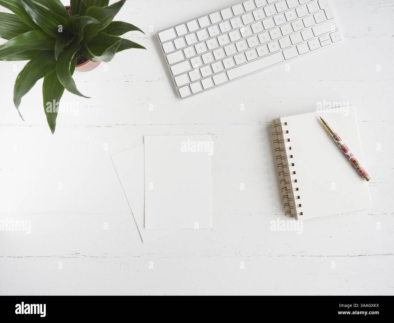 Notebook, blank sheets of paper and pen on white desk table beside a ...