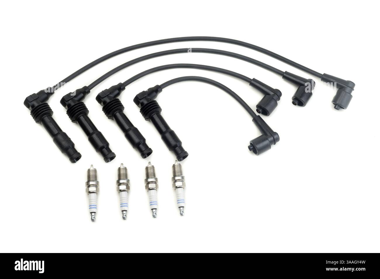 Four spark plugs and a set of high-voltage wires. Isolate on white ...