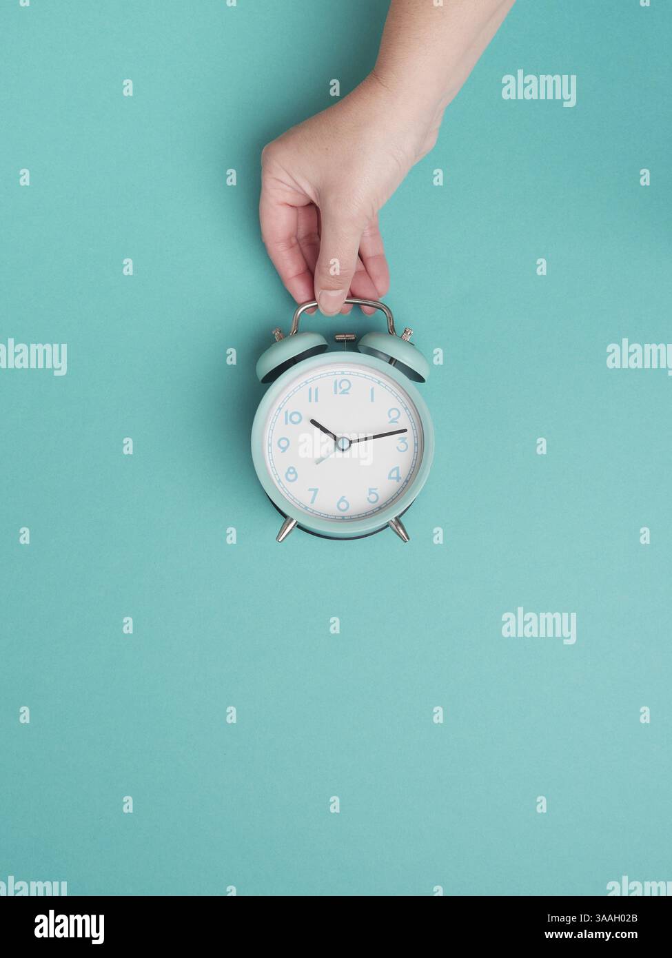 Hand holding by the handle an old style alarm clock. Time management ...