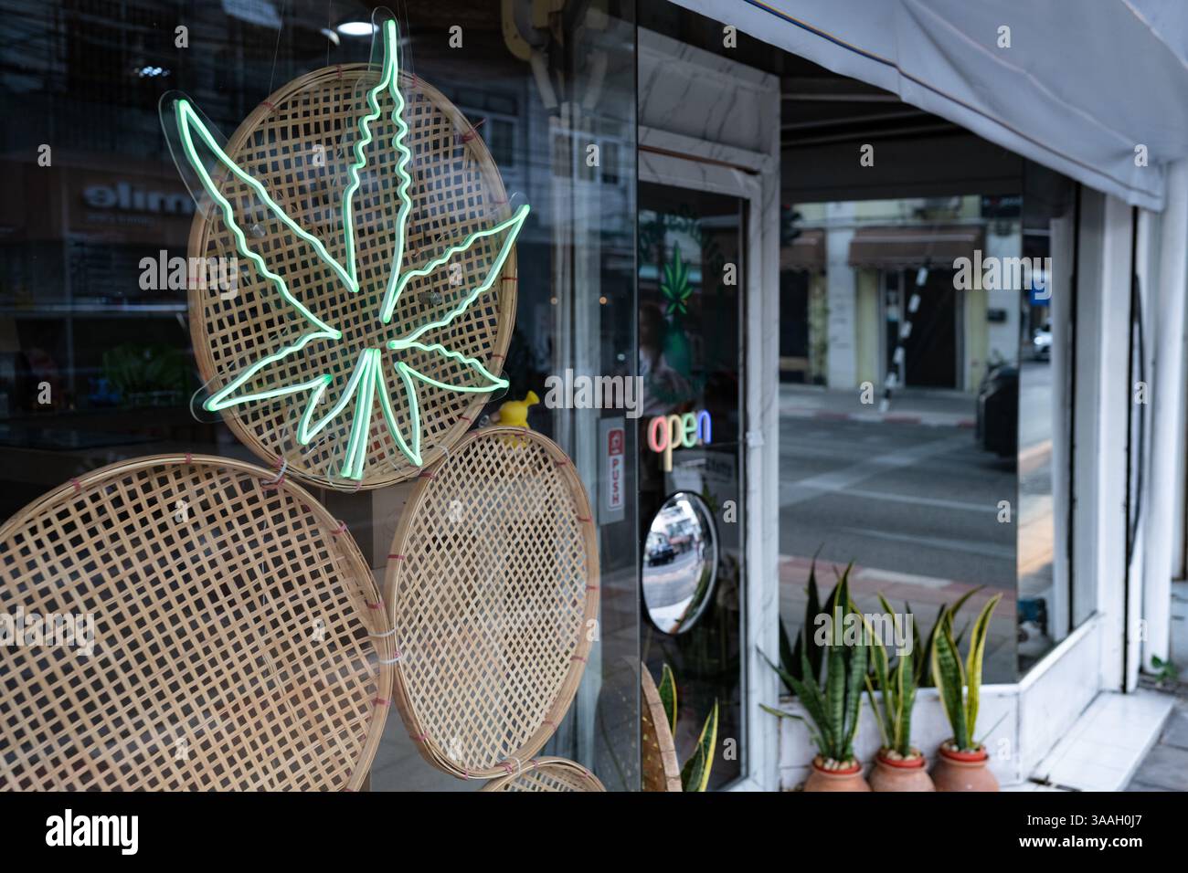 Illuminated neon green cannabis leaf sign in a shop window in central ...