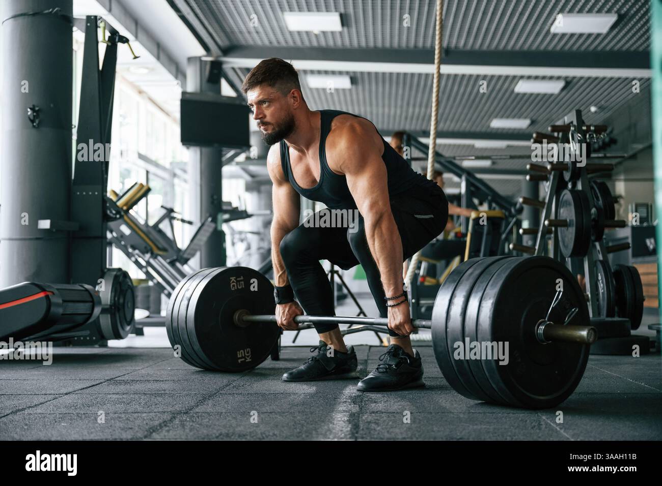 Lifts a barbell. Strong muscular man is working out in the gym Stock ...