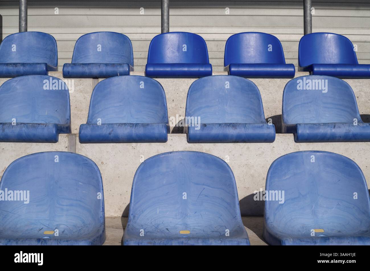 Rows of empty blue plastic seats in a stadium, waiting for the crowd to ...