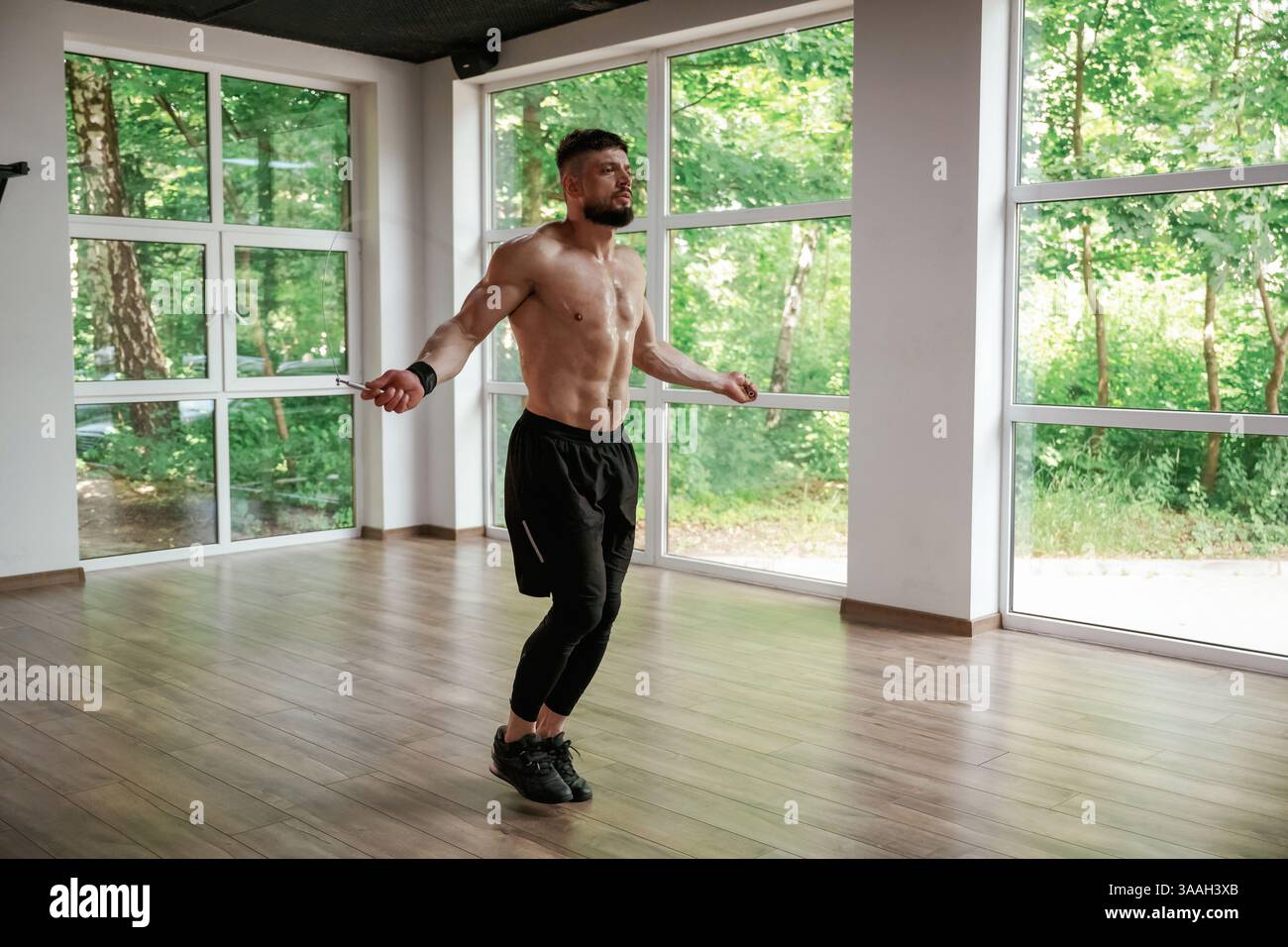 With jumping rope. Strong muscular man is working out in the gym Stock ...