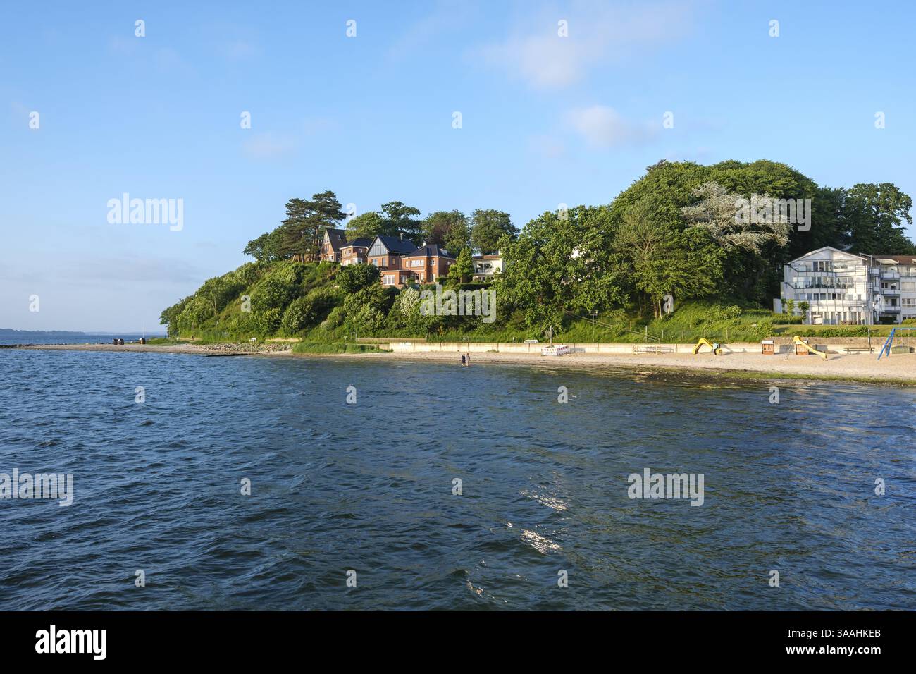Coastal view with trees and buildings on a quiet stretch of beach with ...