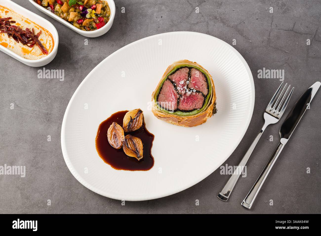 Modern plate of Beef Wellington, caramelized shallots and dark sauce ...