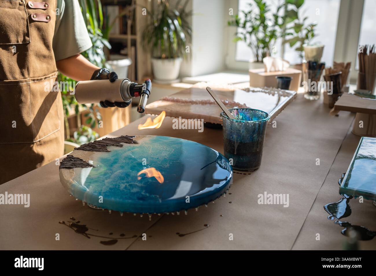 Woman artist hands carefully removes bubbles using gas torch on round ...