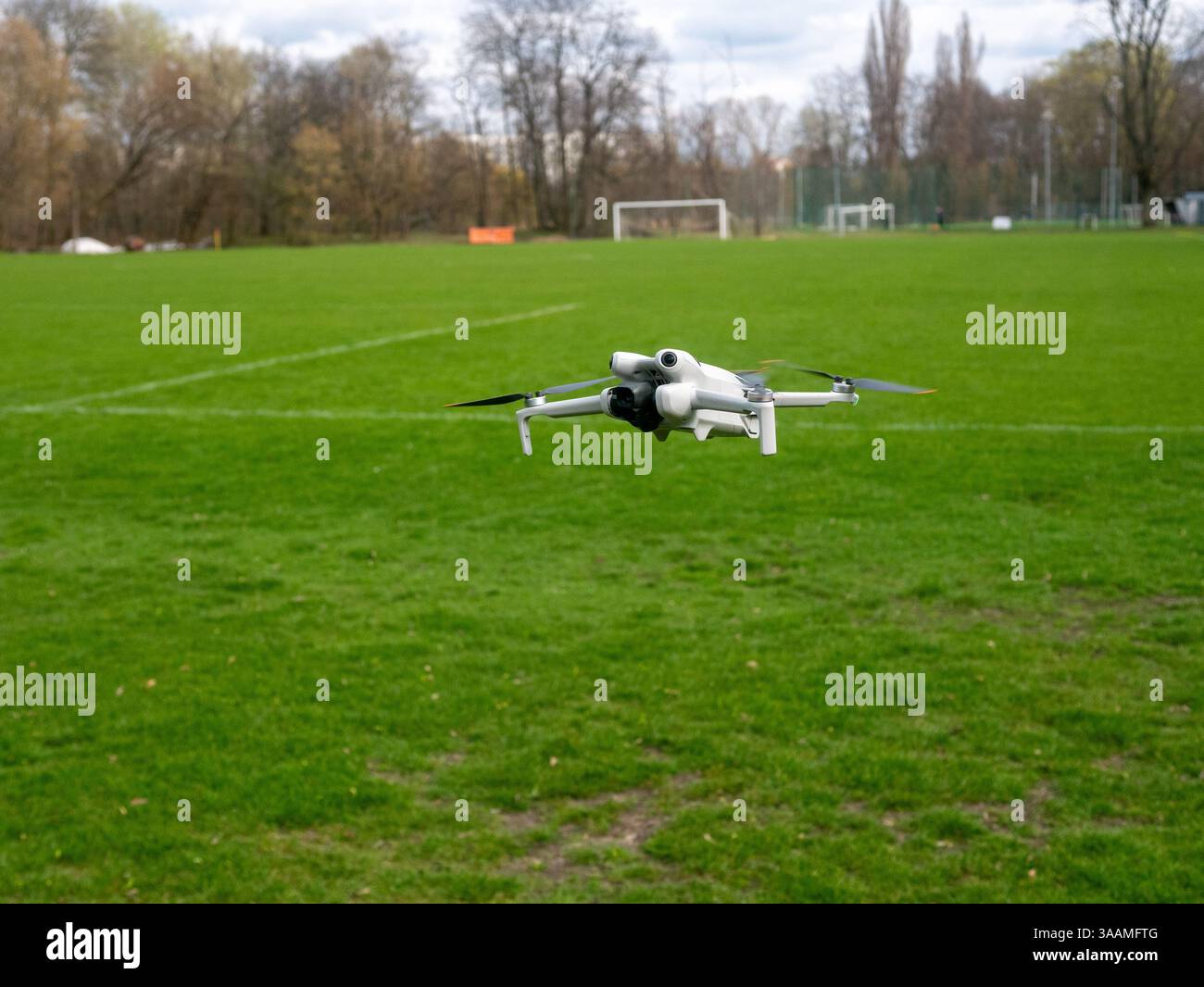 White drone is flying over a green field. The drone is small and white ...
