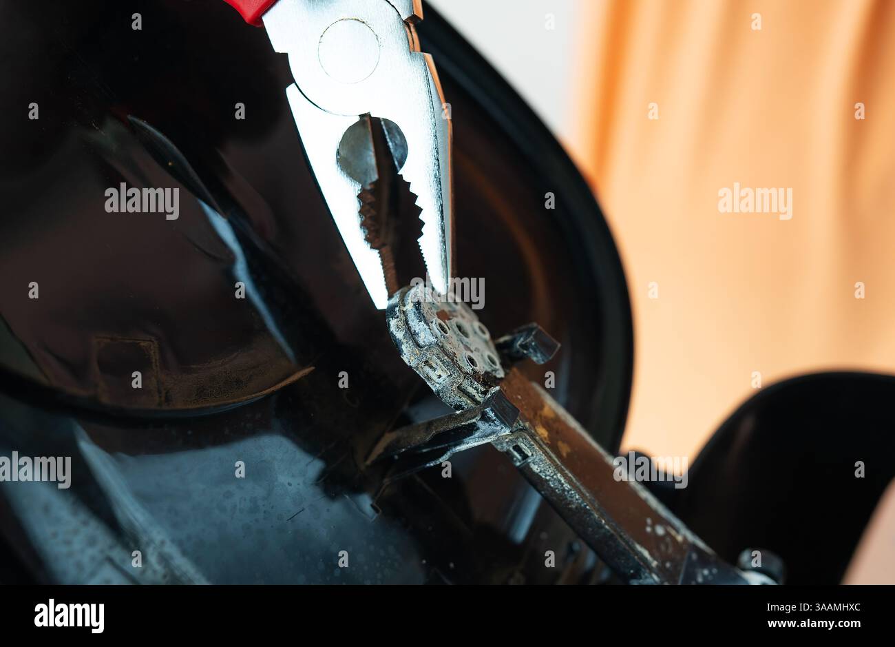 A close-up shot shows a person using pliers to carefully remove a small ...
