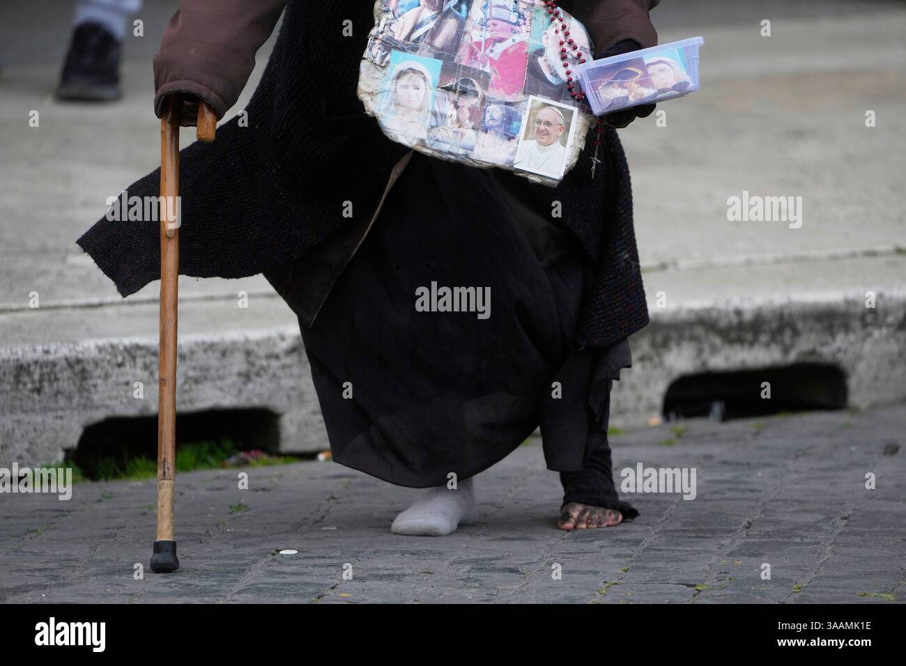 A woman shows pictures of Pope John Paul II and Pope Francis as she ...