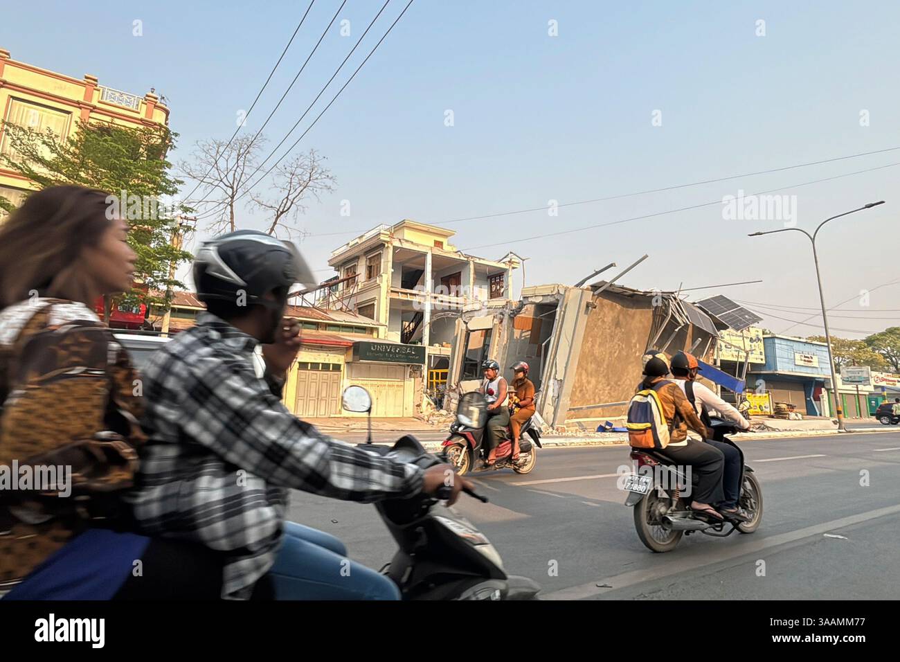 Local residents ride motorbikes near damaged buildings in the aftermath ...