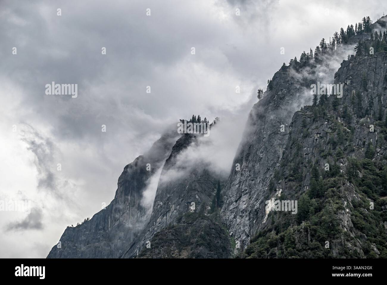 Tall granite cliffs of Yosemite Park, with clouds drifting around the ...