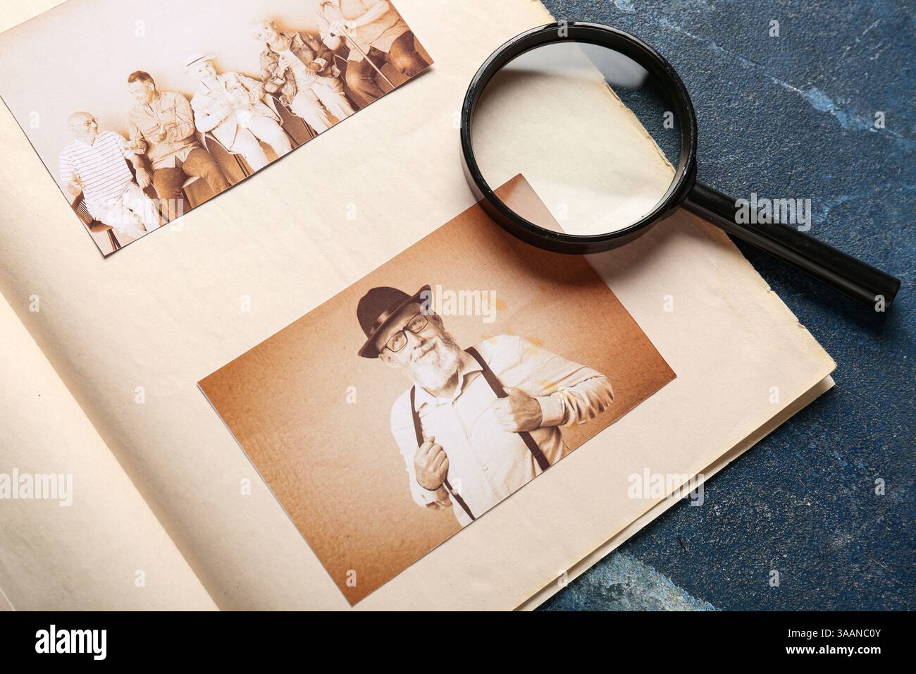 Old album with photos of relatives and magnifier on dark blue ...