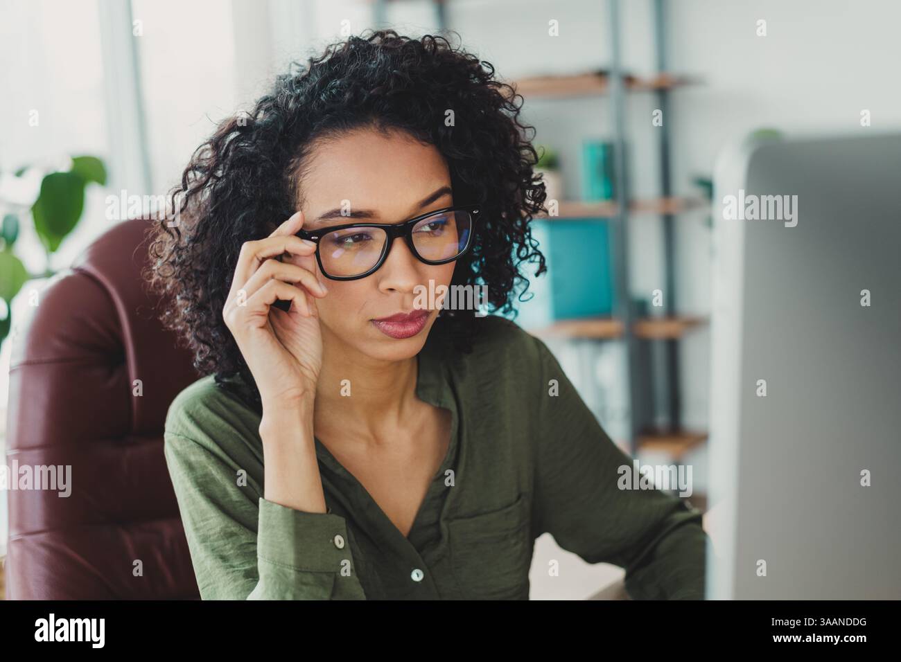 Young professional woman working at an office desk while adjusting her ...
