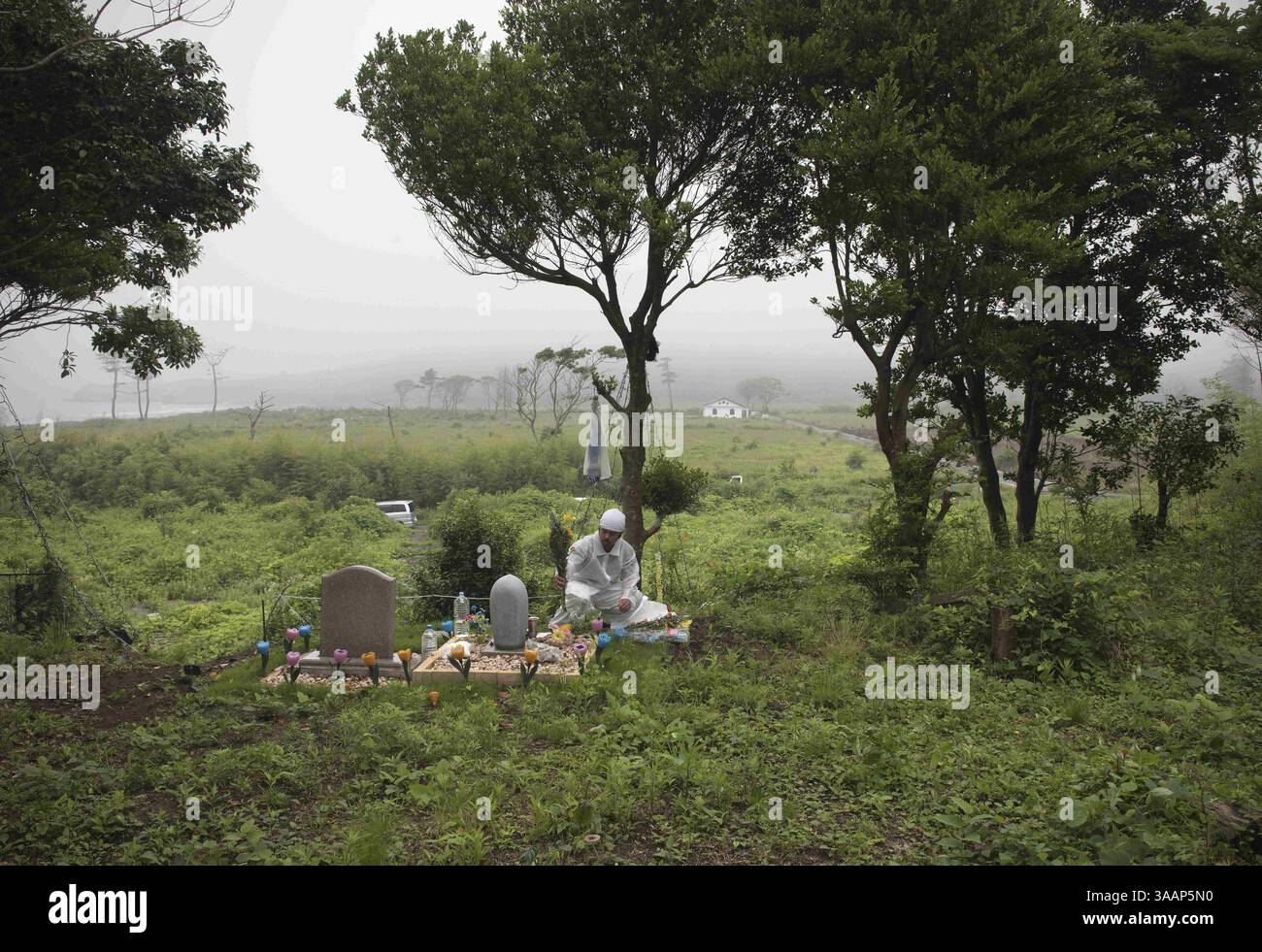 July 5, 2015 - Okuma, Fuksuhima, Japan - NORIO KIMURA offers flowers to the small stone statue ...