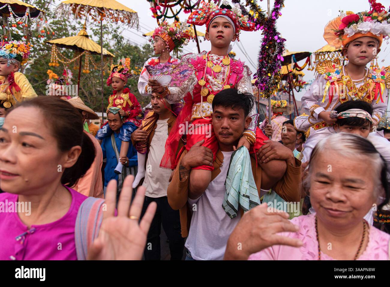 Young ethnic Shan boys dressed in colorful costumes are seen carried on ...