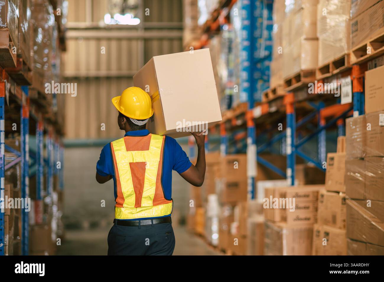 African black male warehouse worker carrying box in storehouse building ...