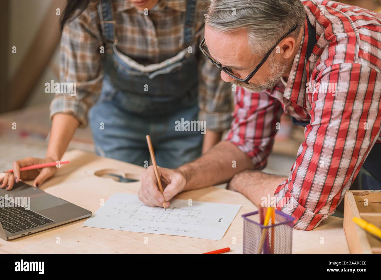 Professional senior carpenter man working with women team design wooden ...