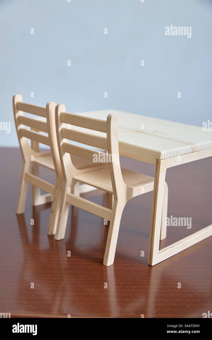 Two miniature wooden chairs are placed beside a small wooden table on a ...