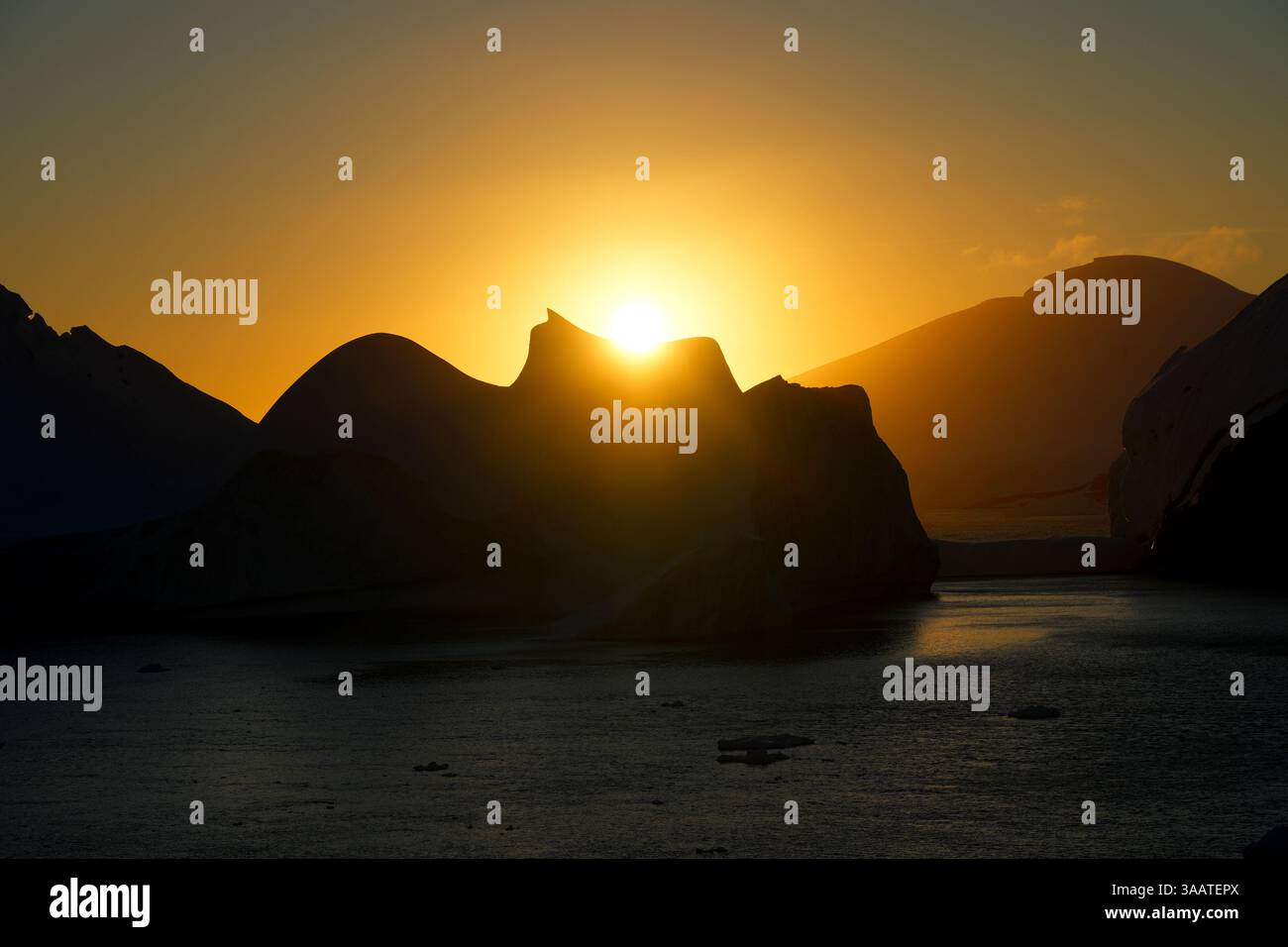 Sunset over an iceberg blocking the southern end of Lemaire Channel off ...