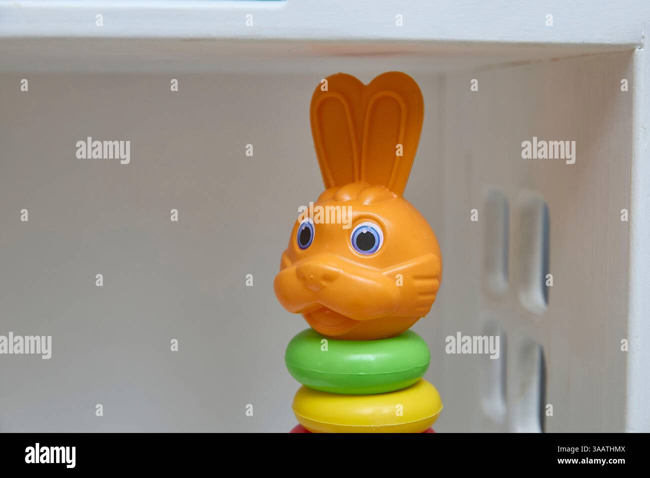 A vibrant rabbit toy with big eyes sits atop colorful stacked rings in ...