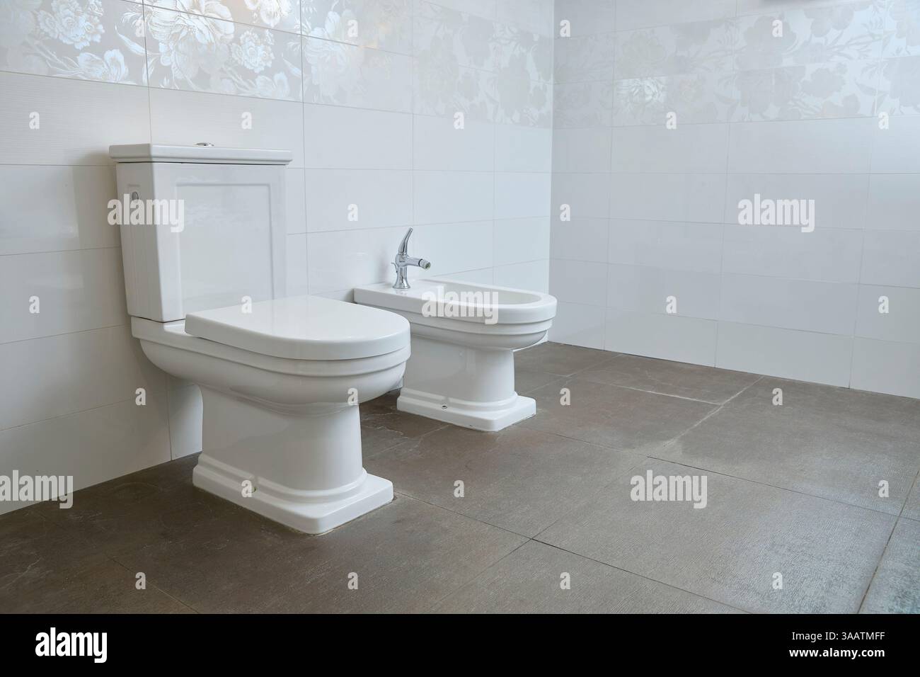 Modern bathroom featuring a sleek toilet and bidet side by side. The ...