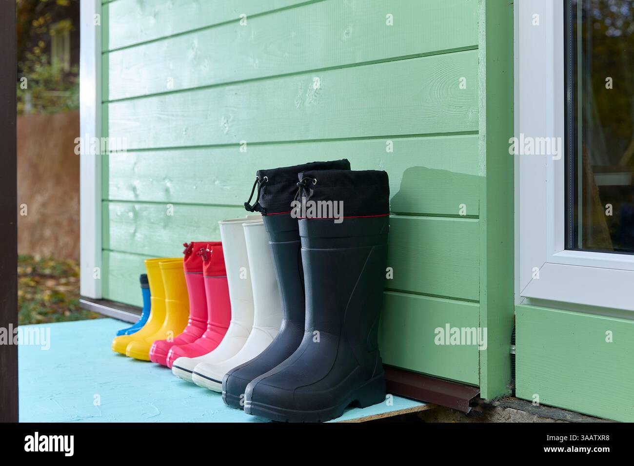 Various sizes of rain boots in diverse colors neatly lined up against a ...