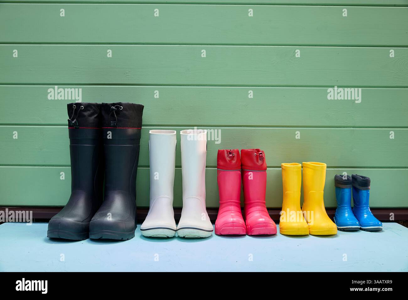 A collection of rain boots in various sizes and colors is neatly lined ...