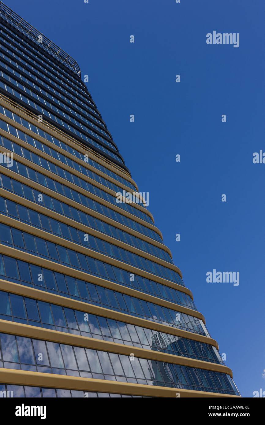 A close-up of a tall skyscraper corner against the sky. Blue glass ...