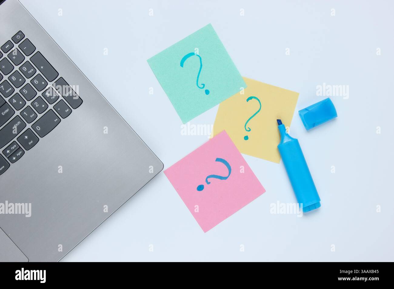 Laptop, memo pieces of paper with drawn question marks and felt-tip pen ...