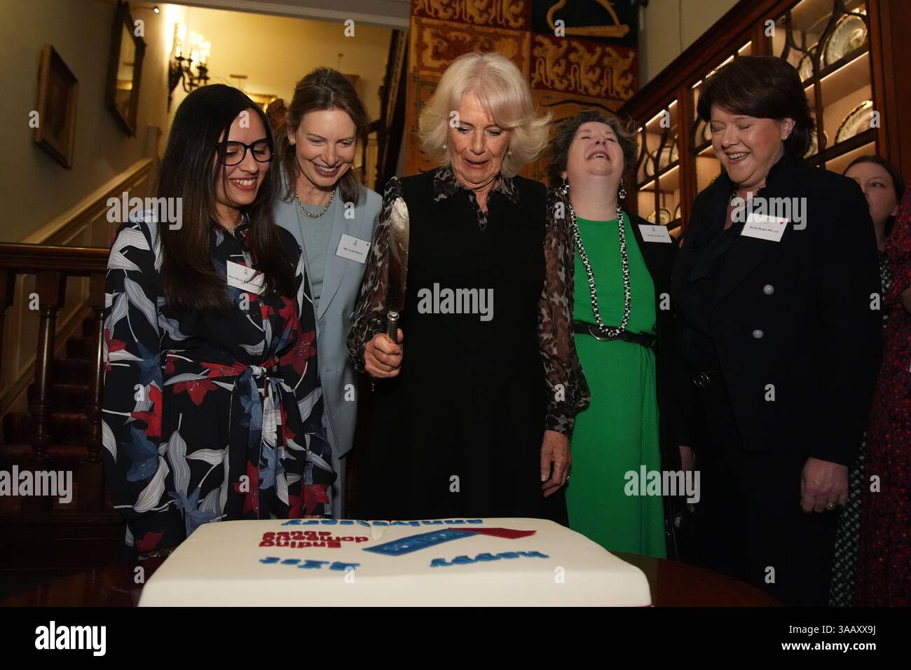 Queen Camilla (right), patron of SafeLives, cuts a cake watched by ...