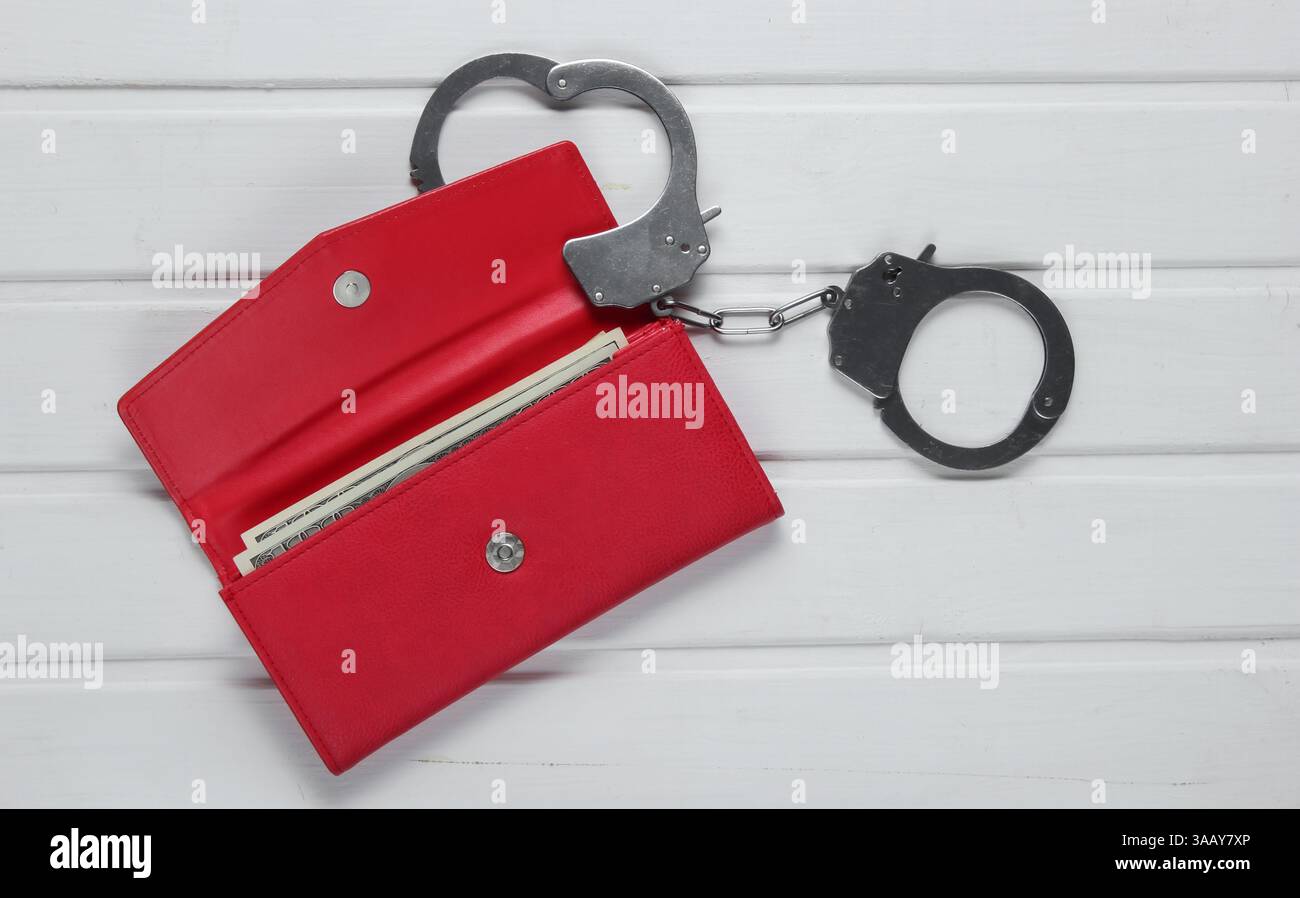 Steel handcuffs with red leather wallet on white table. Theft, criminal ...