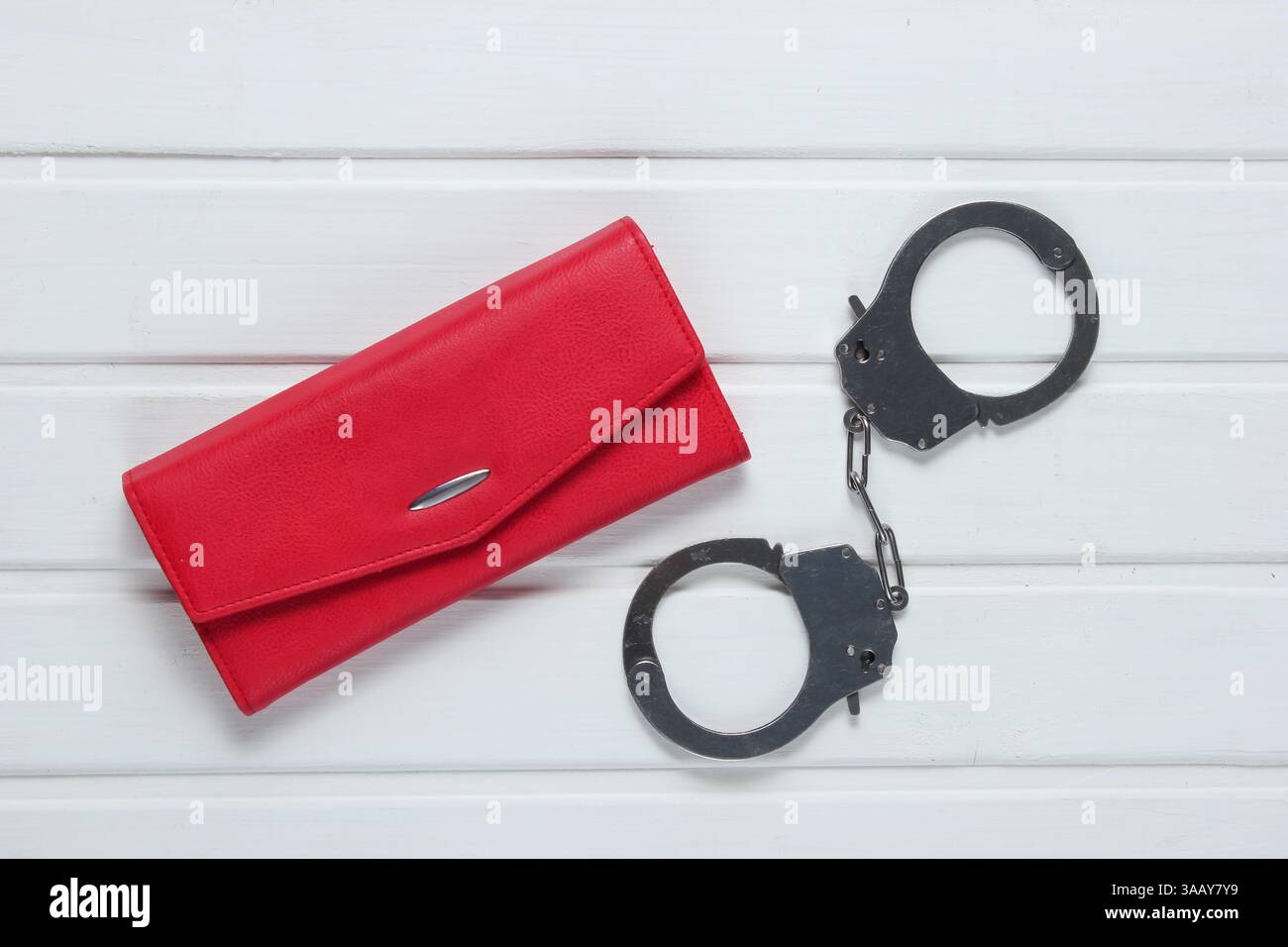 Steel handcuffs with red leather wallet on white table. Theft, criminal ...