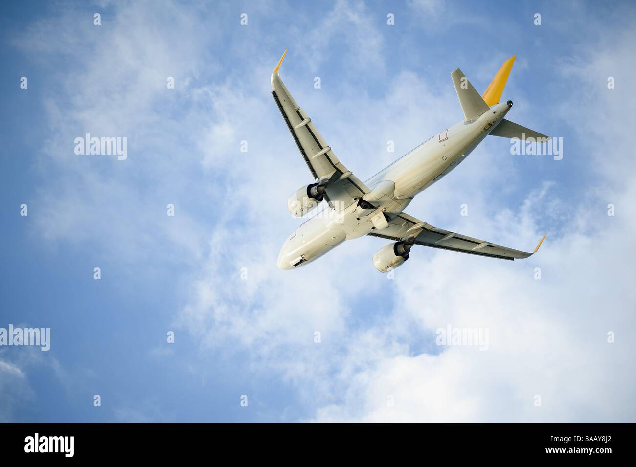 White commercial passenger jet flying in blue sky, bottom view ...