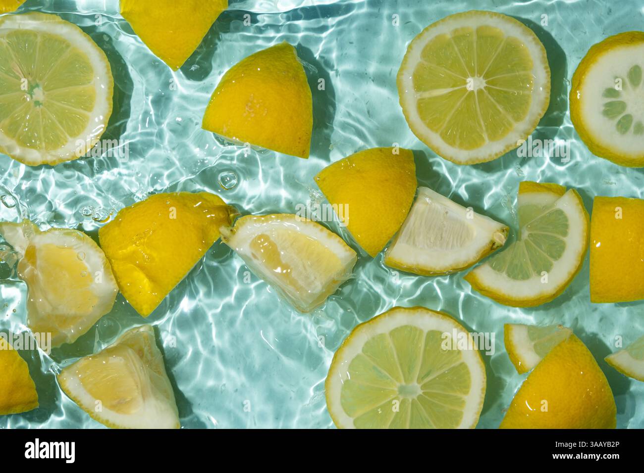 Refreshing turquoise citrus background with floating yellow lemon pieces Stock Photo - Alamy