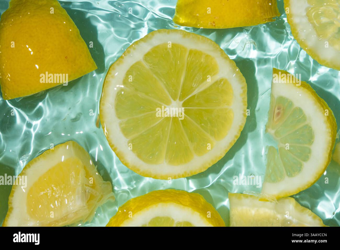 Refreshing turquoise citrus background with floating yellow lemon pieces Stock Photo - Alamy