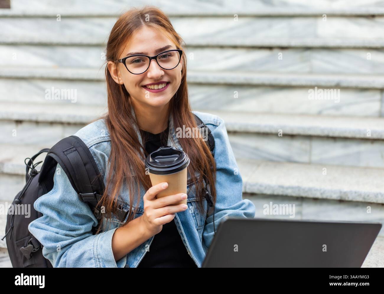 Happy modern woman student in denim jacket and backpack sitting on the ...